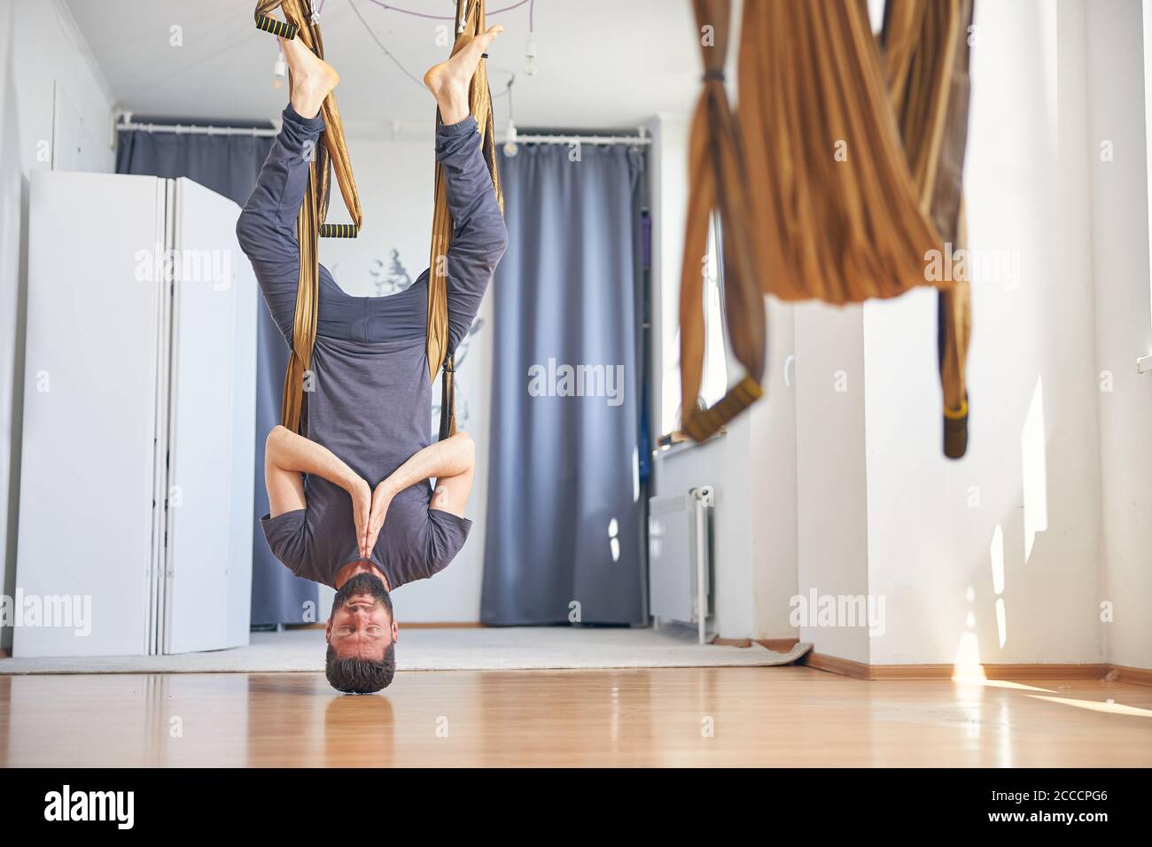Fit man doing an aerial yoga headstand Stock Photo - Alamy