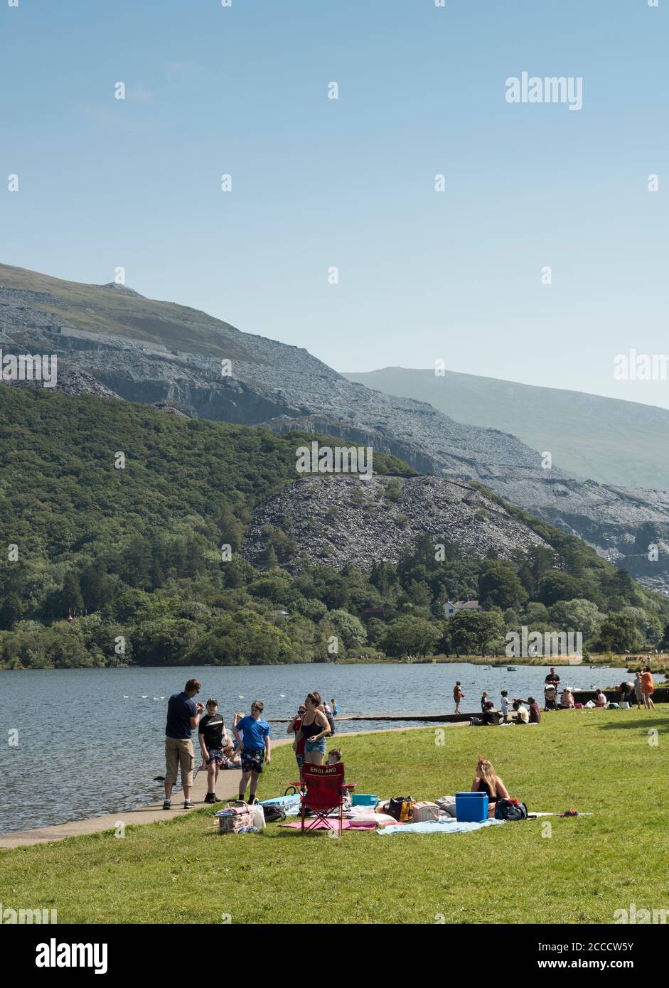 A group of people relaxing and picnicking along the popular Llyn Padarn ...