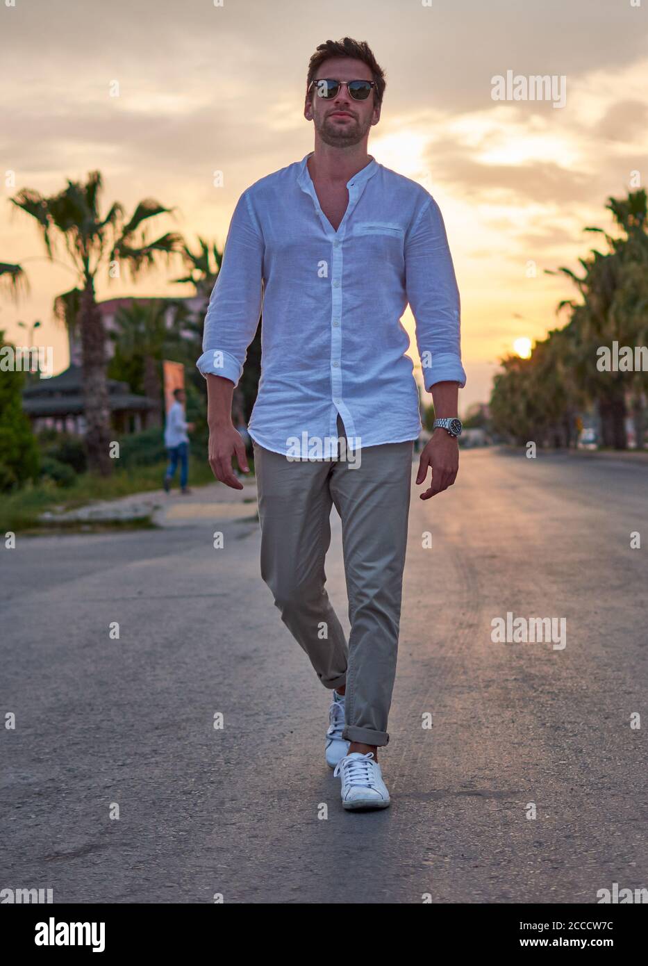 Vertical shot of a male model walking down the street on background of ...