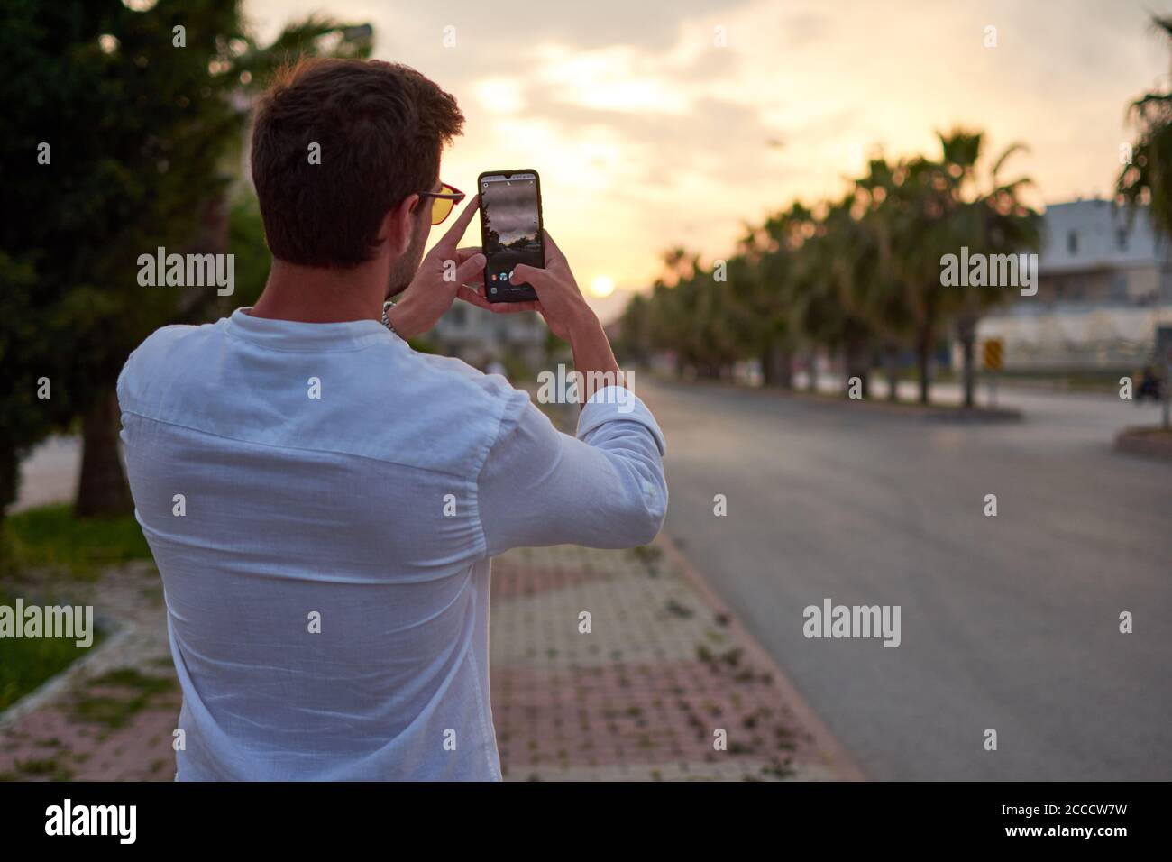Male model taking a picture of a beautiful sunset Stock Photo - Alamy