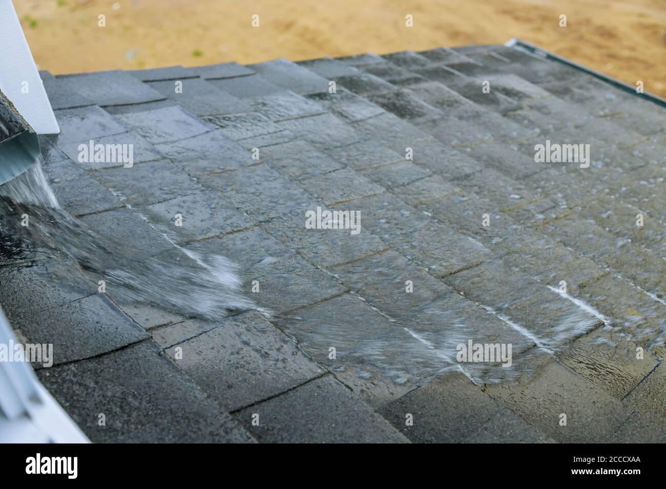 Drainpipe at the edge of the roof water flows on the roof during a ...