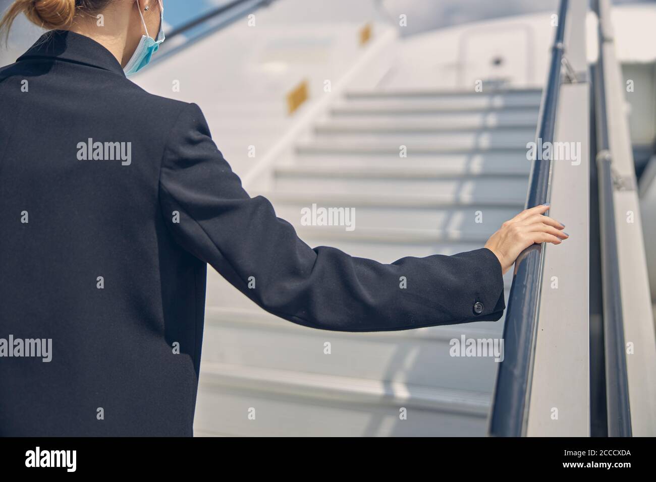 Blonde woman in a mask leaning on the handrail Stock Photo - Alamy
