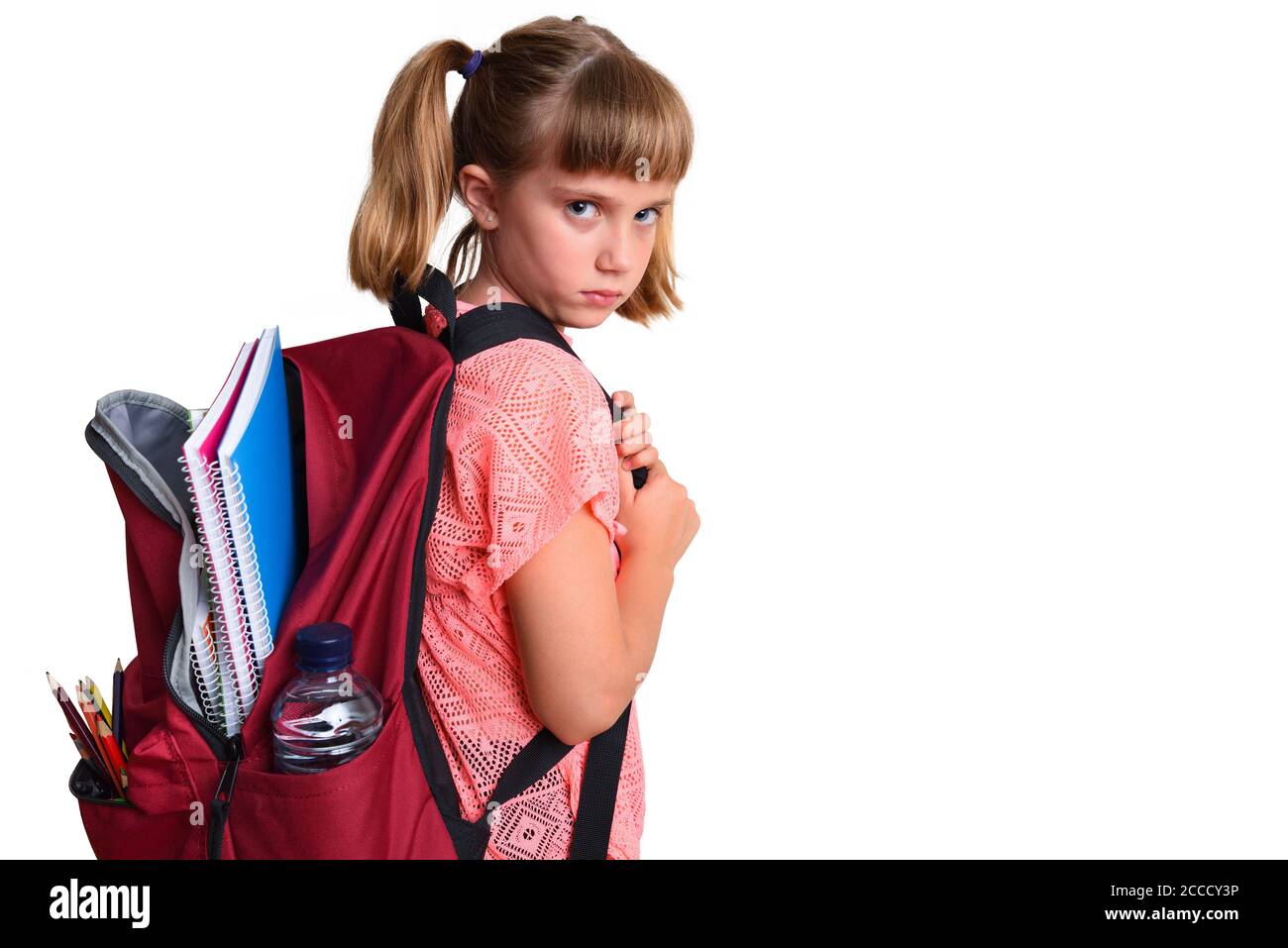 Little and sad girl with backpack on her back with school supplies with ...