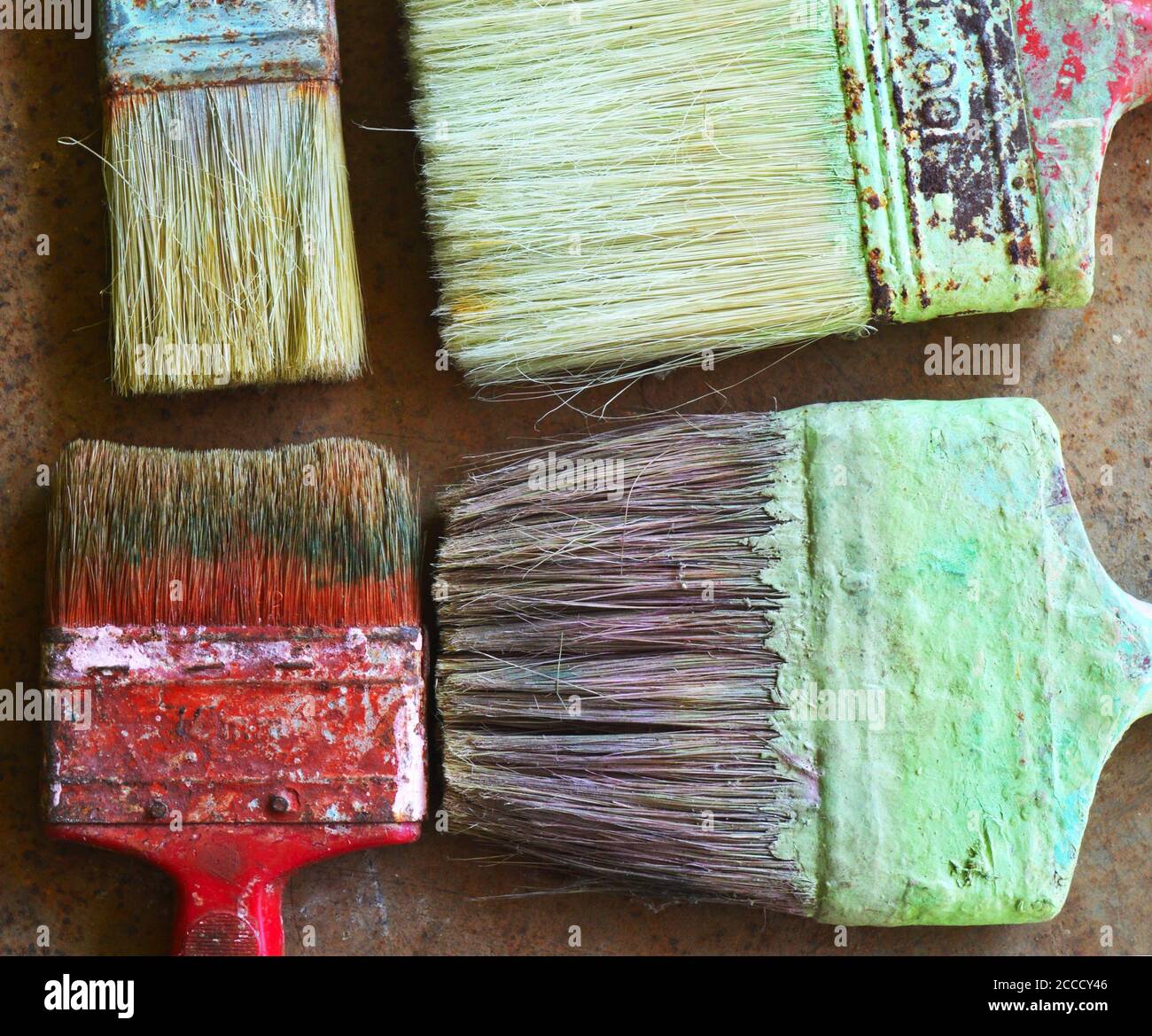 image shows some used paint brushes placed on a brown surface. Image ...