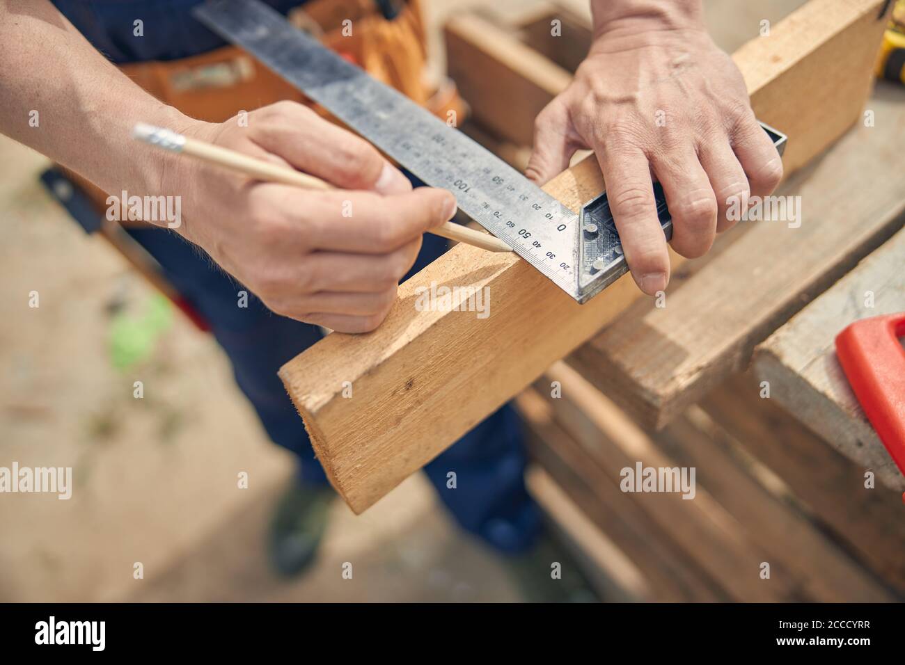 Carpenter measuring the length on one side of the wood Stock Photo - Alamy