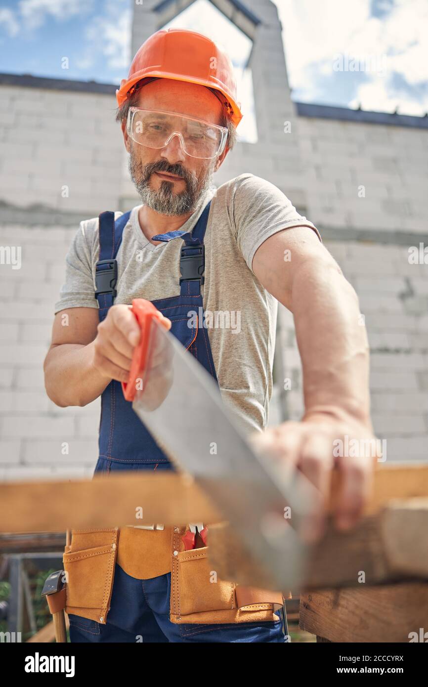 Focused male worker using a hand saw Stock Photo - Alamy