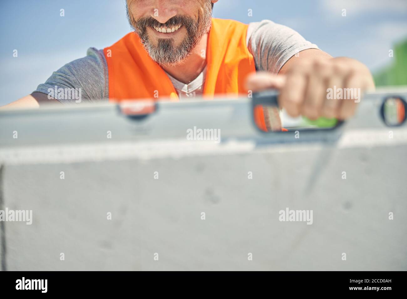 Smiling constructor worker using a spirit level Stock Photo - Alamy