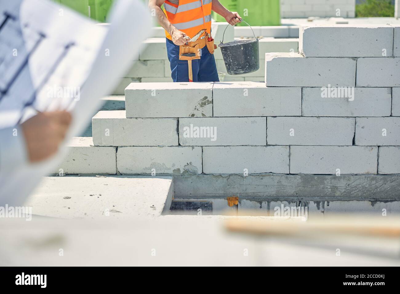Bricklayer in a reflective waistcoat using a trowel Stock Photo - Alamy