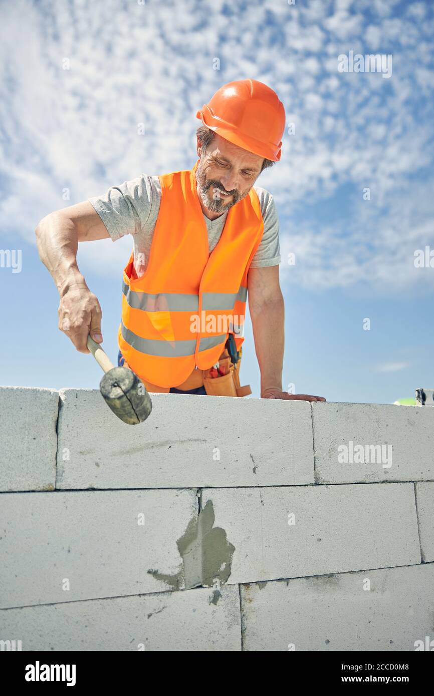 Smiling mason with a construction tool outdoors Stock Photo - Alamy