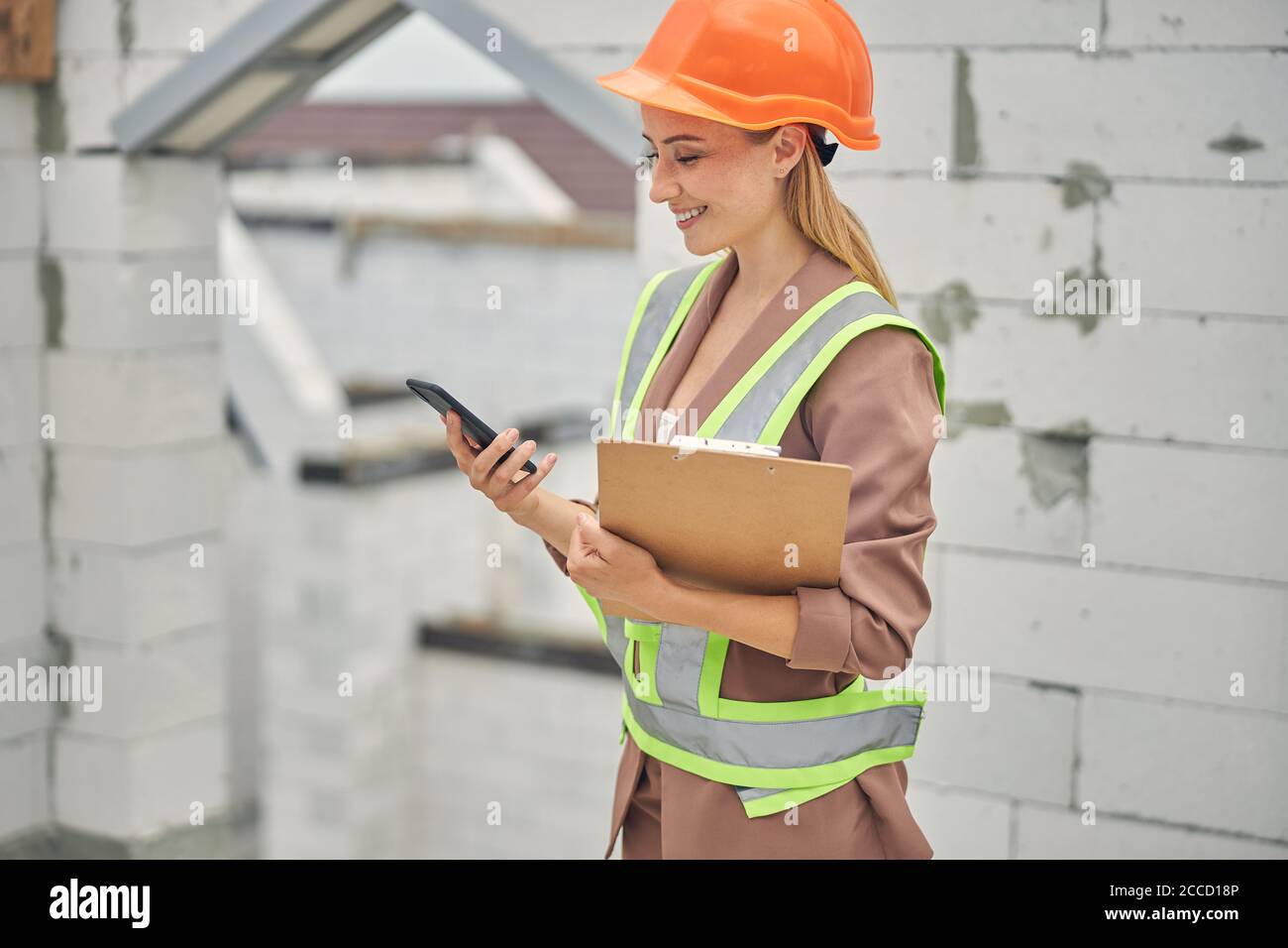 Pleased blonde woman engineer holding a clipboard Stock Photo - Alamy