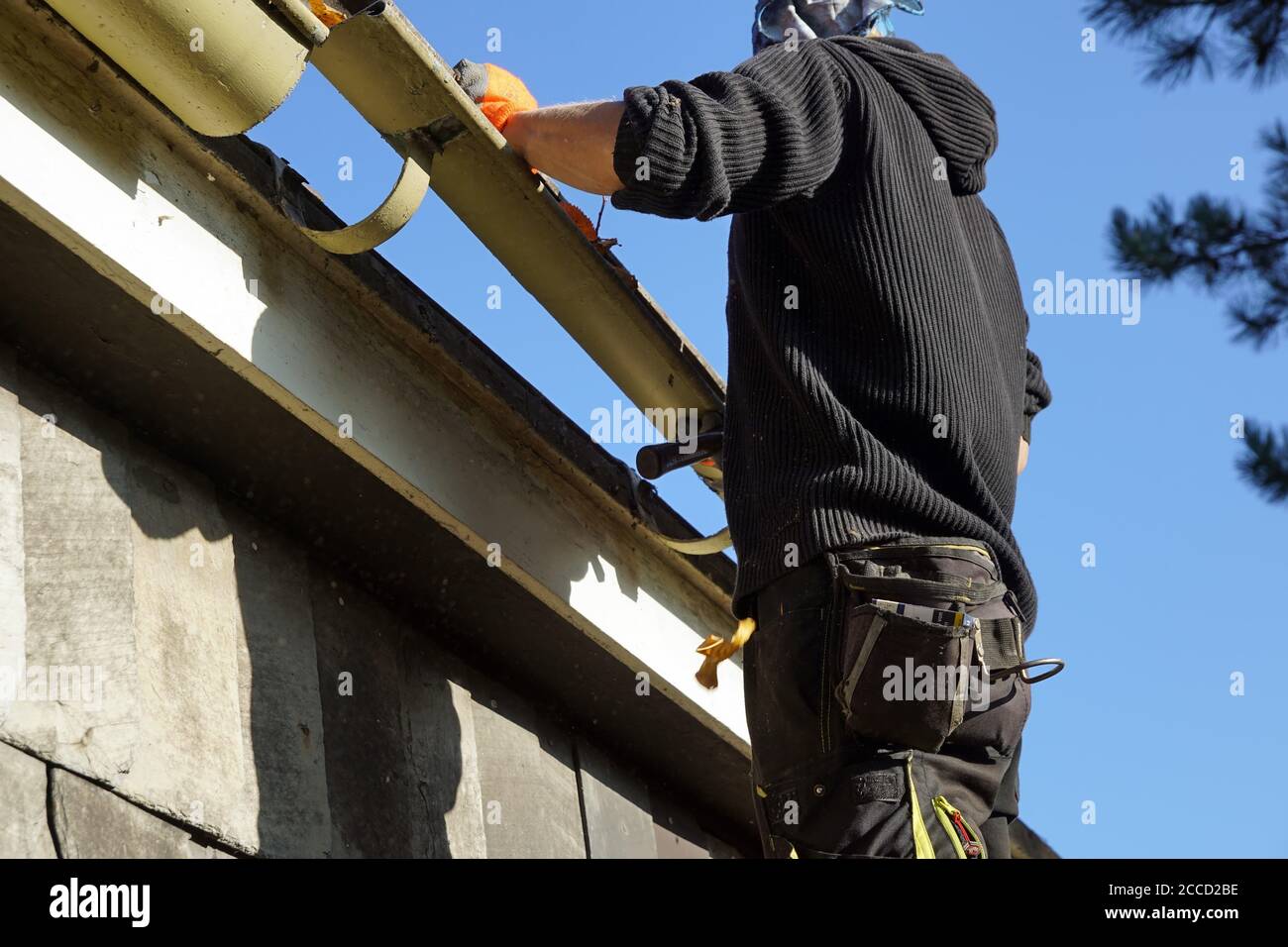 Low angle shot of a construction worker working and fixing a roof Stock ...