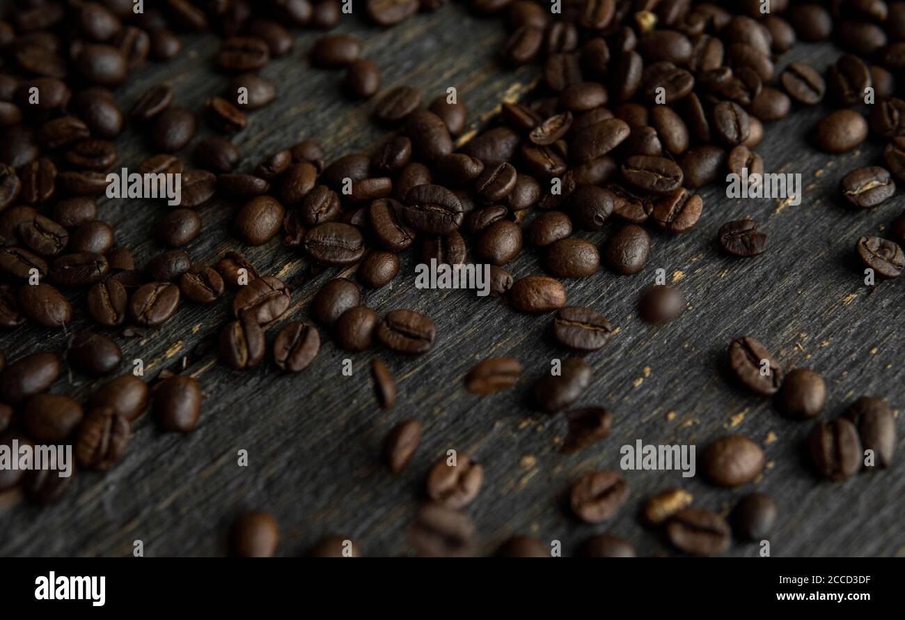 Roasted arabica coffee beans scattered on a wooden table. Fresh coffee ...
