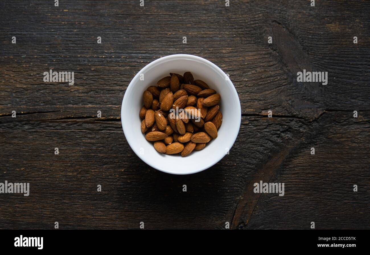 Almonds in a small plate on a vintage wooden table. Almond is a healthy ...