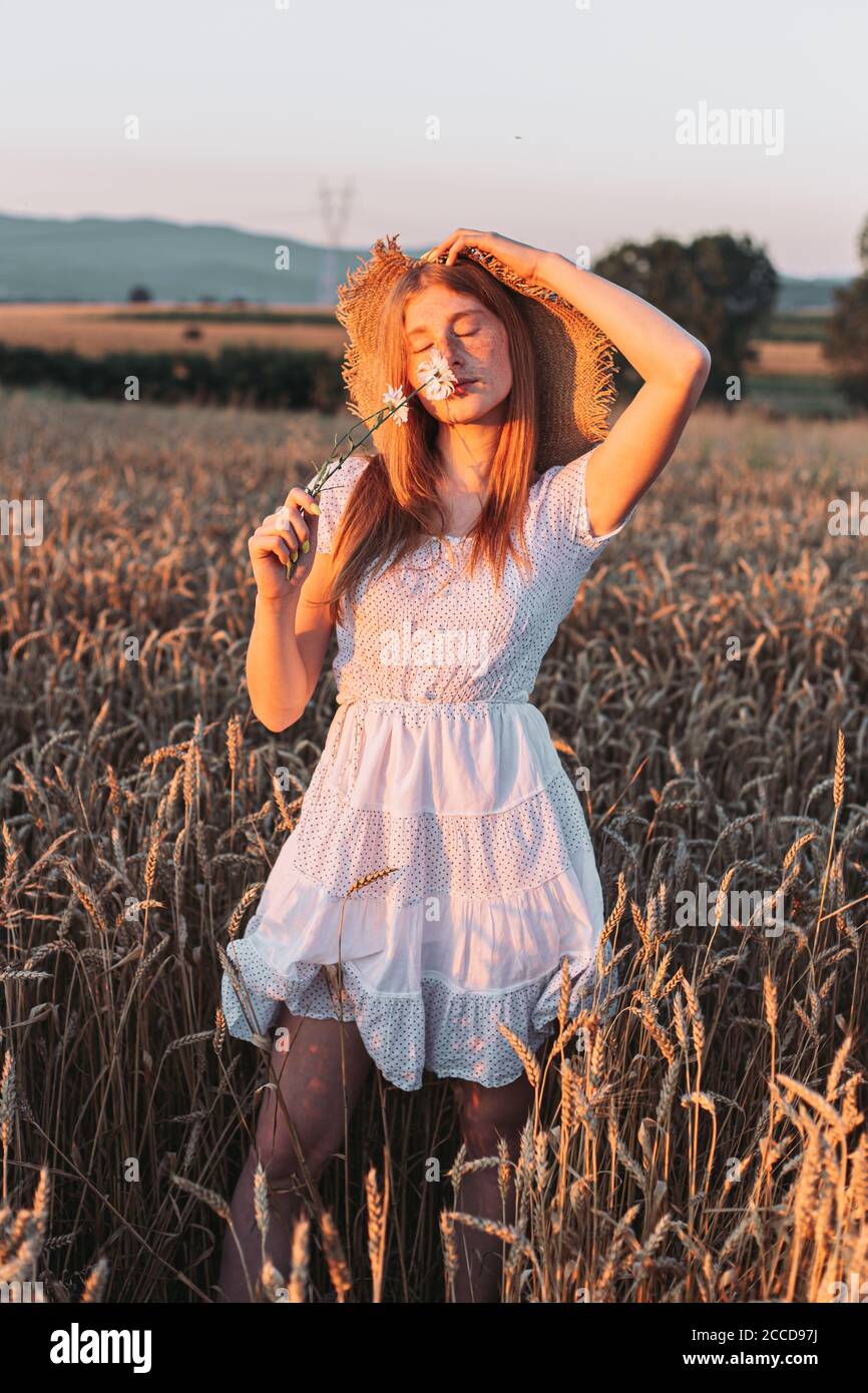 Beautiful ginger girl smelling flower in the wheat field in the ...