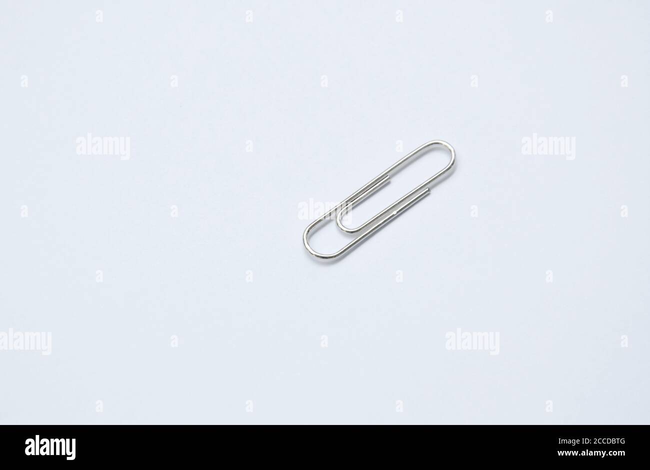 Silver paper clip on white background Stock Photo - Alamy