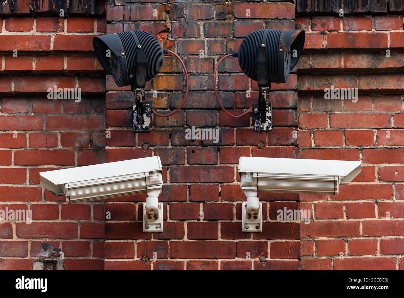 Two surveillance cameras on a red brick wall, with infrared spotlights ...