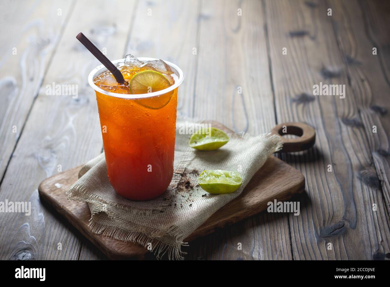 ice tea with slice of lemon in plastic cup on the wooden background ...