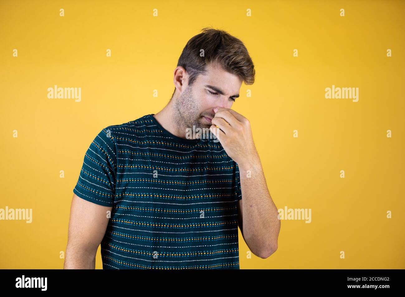 Young beautiful woman standing over isolated blue background smelling ...