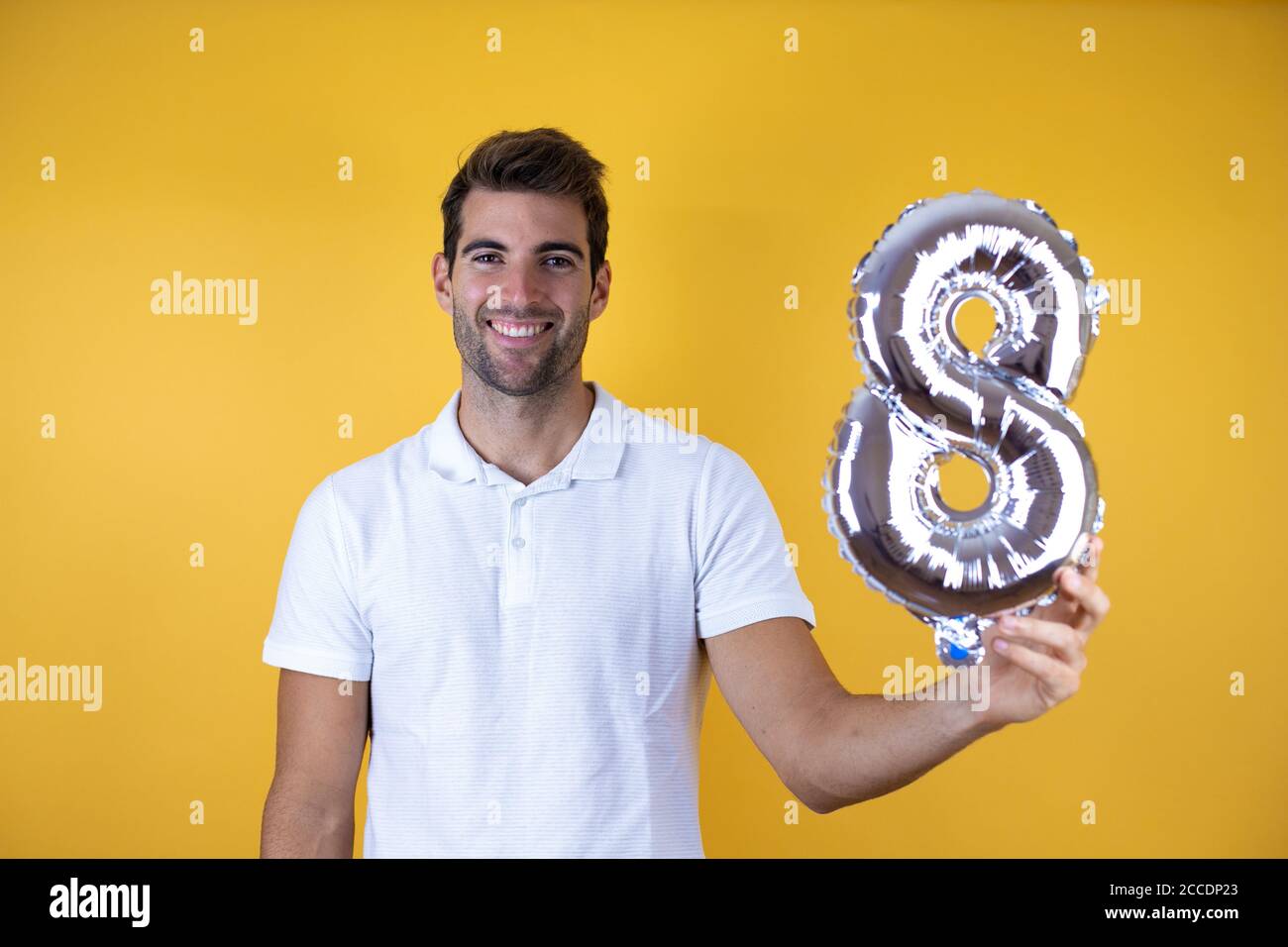 Young handsome man smiling holding a number eight. Aniversary or ...