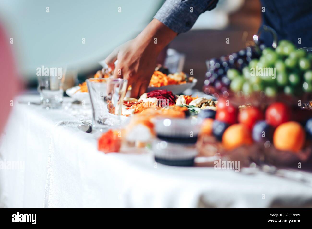 Long table covered with a tablecloth on which there is a lot of food ...