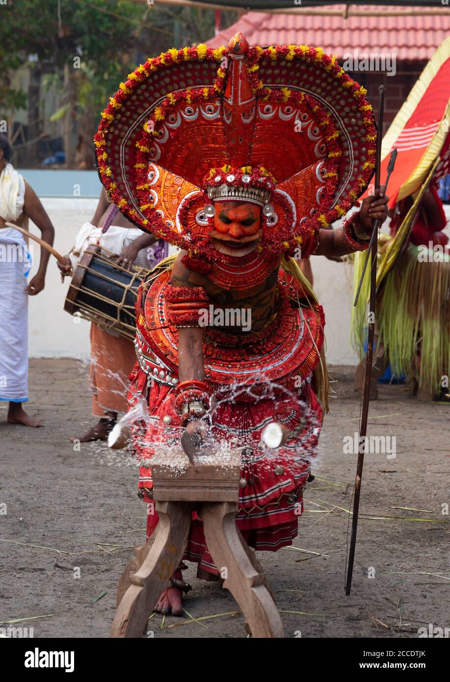 A Theyyam performer breaking coconut as a ritual Stock Photo - Alamy