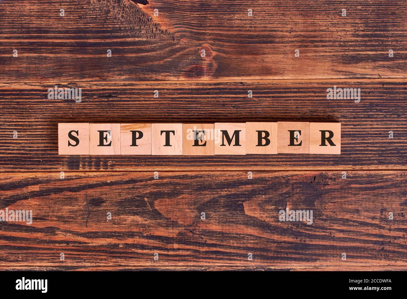 September words on wood block. Dark brown wooden background. Top view ...