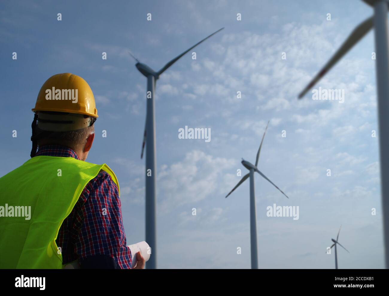 Engineer in a wind turbine. A man in a helmet supervises the operation ...