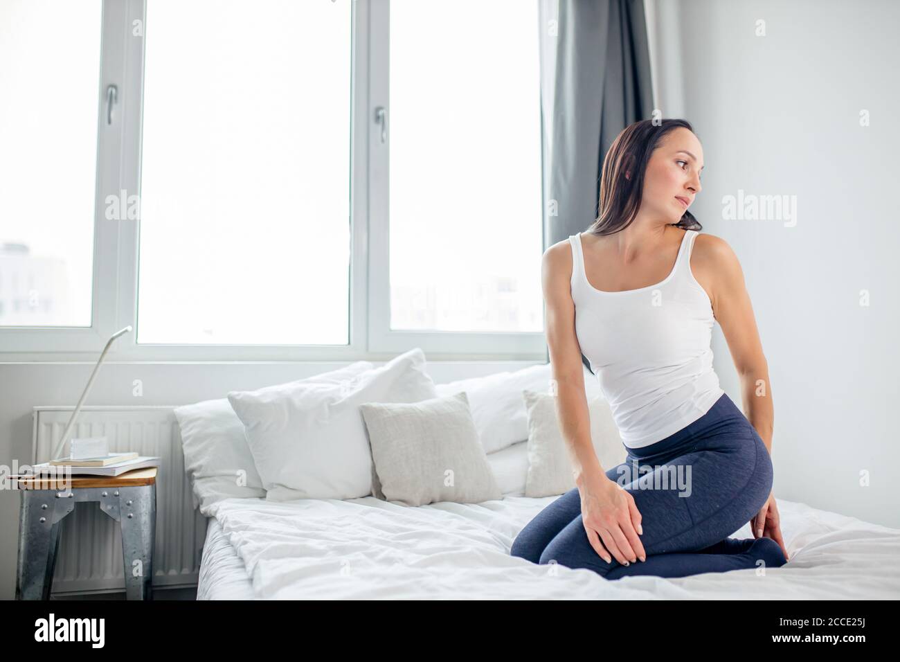 sporty beautiful caucasian woman stretch neck and whole body on bed at ...