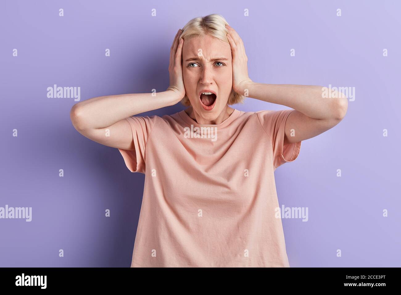 nervous girl closing ears with hands, shouting, looking at camera over ...