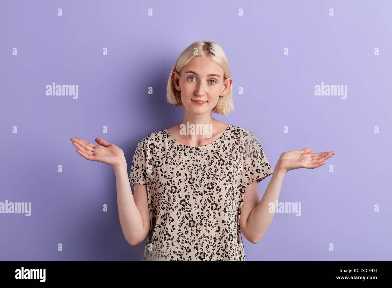 Portrait of a confused young attractive girl shrugging shoulders ...