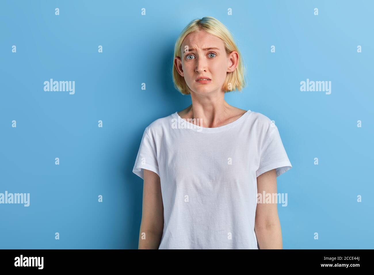puzzzled worried woman in white T-shirt doesn't know what to do ...