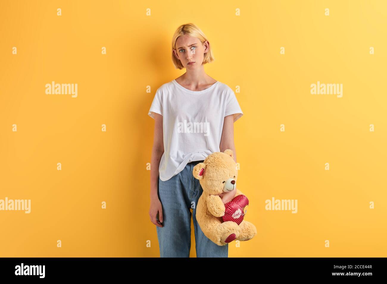 depressed girl in white T-shirt and jeans with toy in hands posing to ...