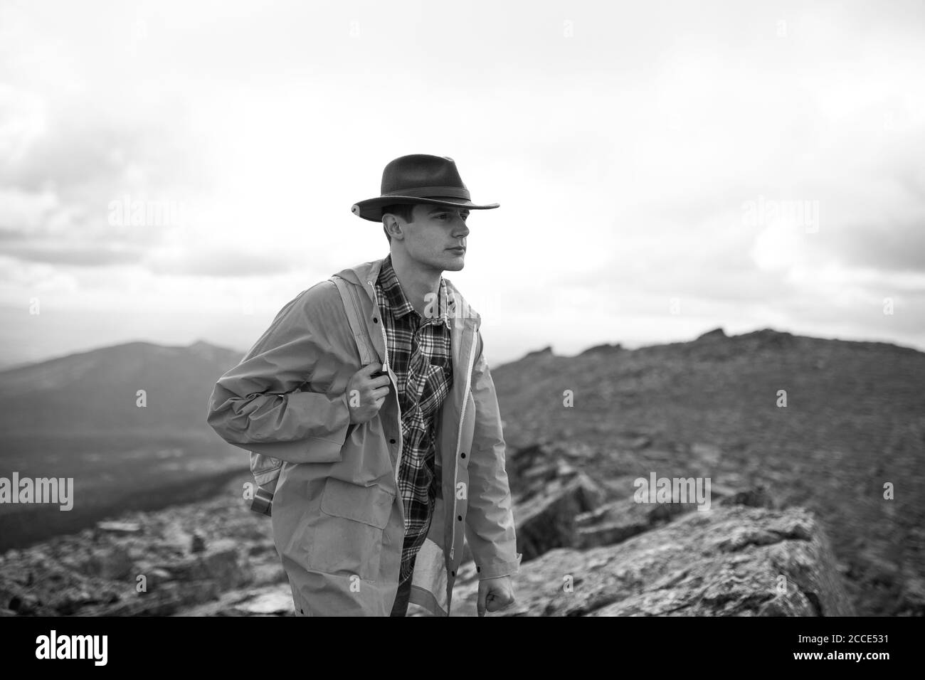 serious handsome pensive male hiker on a top of a mountain, white and ...