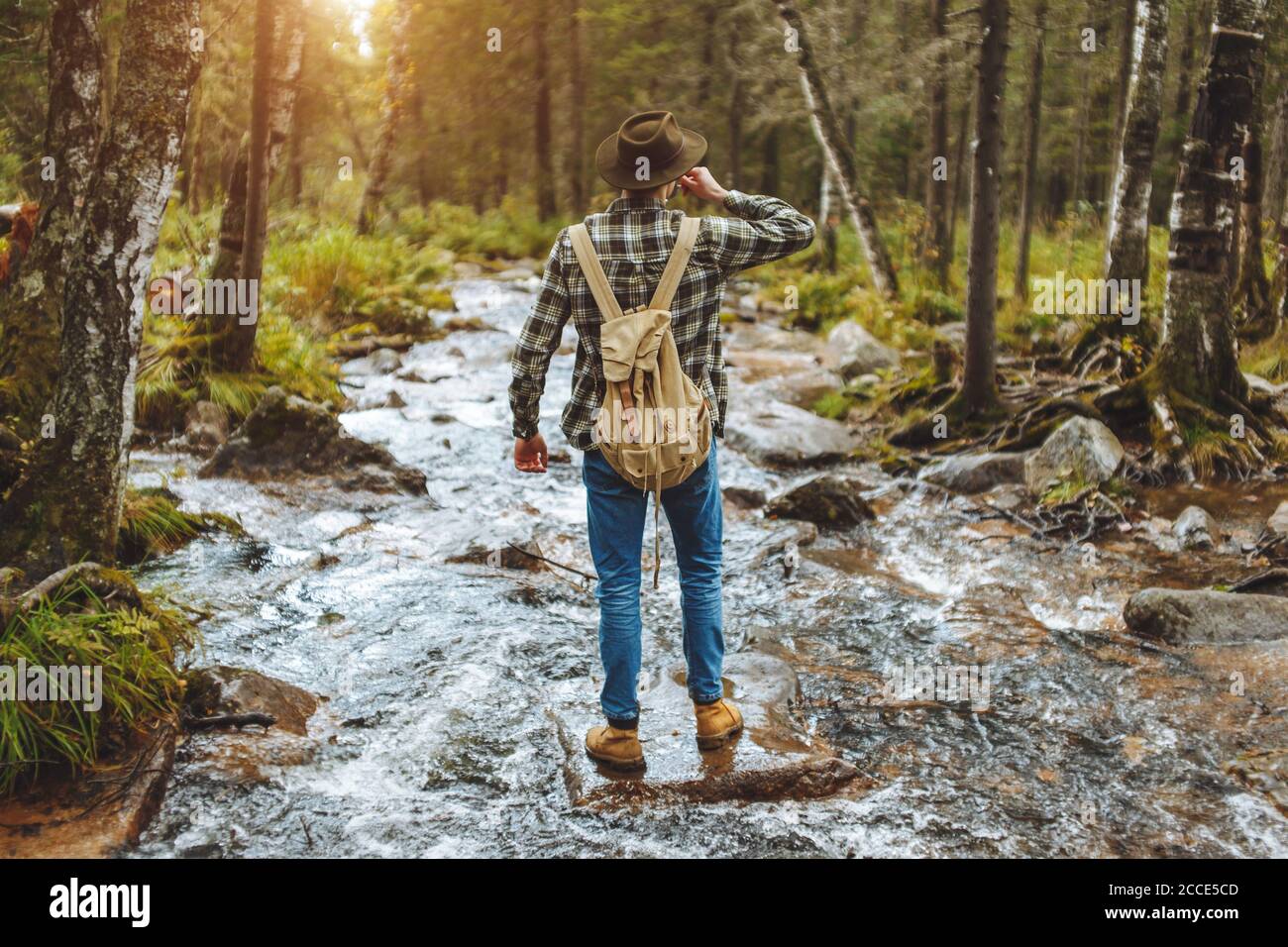 man gets pleasure from drinking cold water of stream, back view full ...