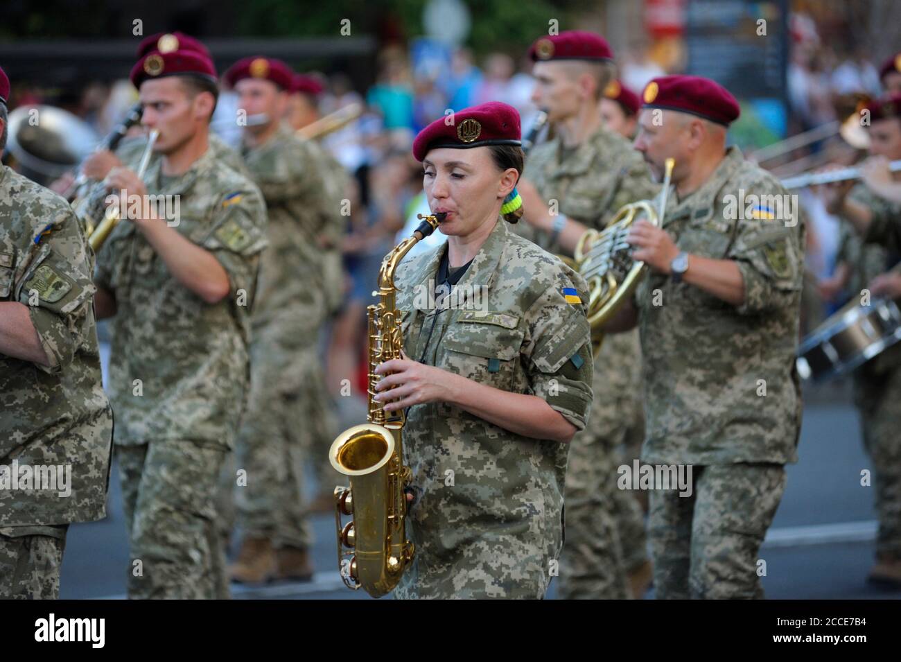 Female musician in military uniform playing saxophone on the street ...