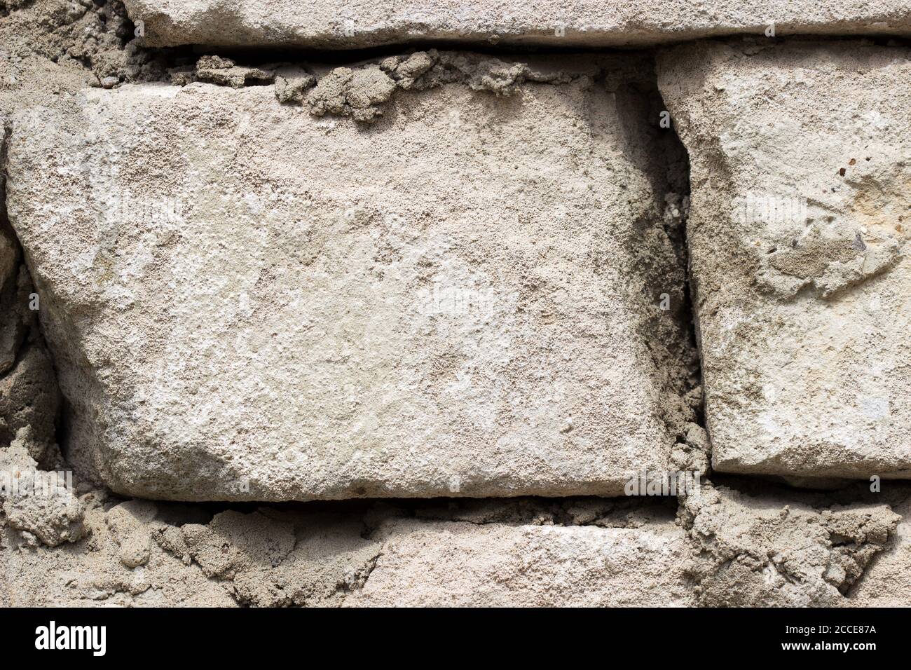 An old crumbling wall of cauldron and cement, illuminated by the sun ...