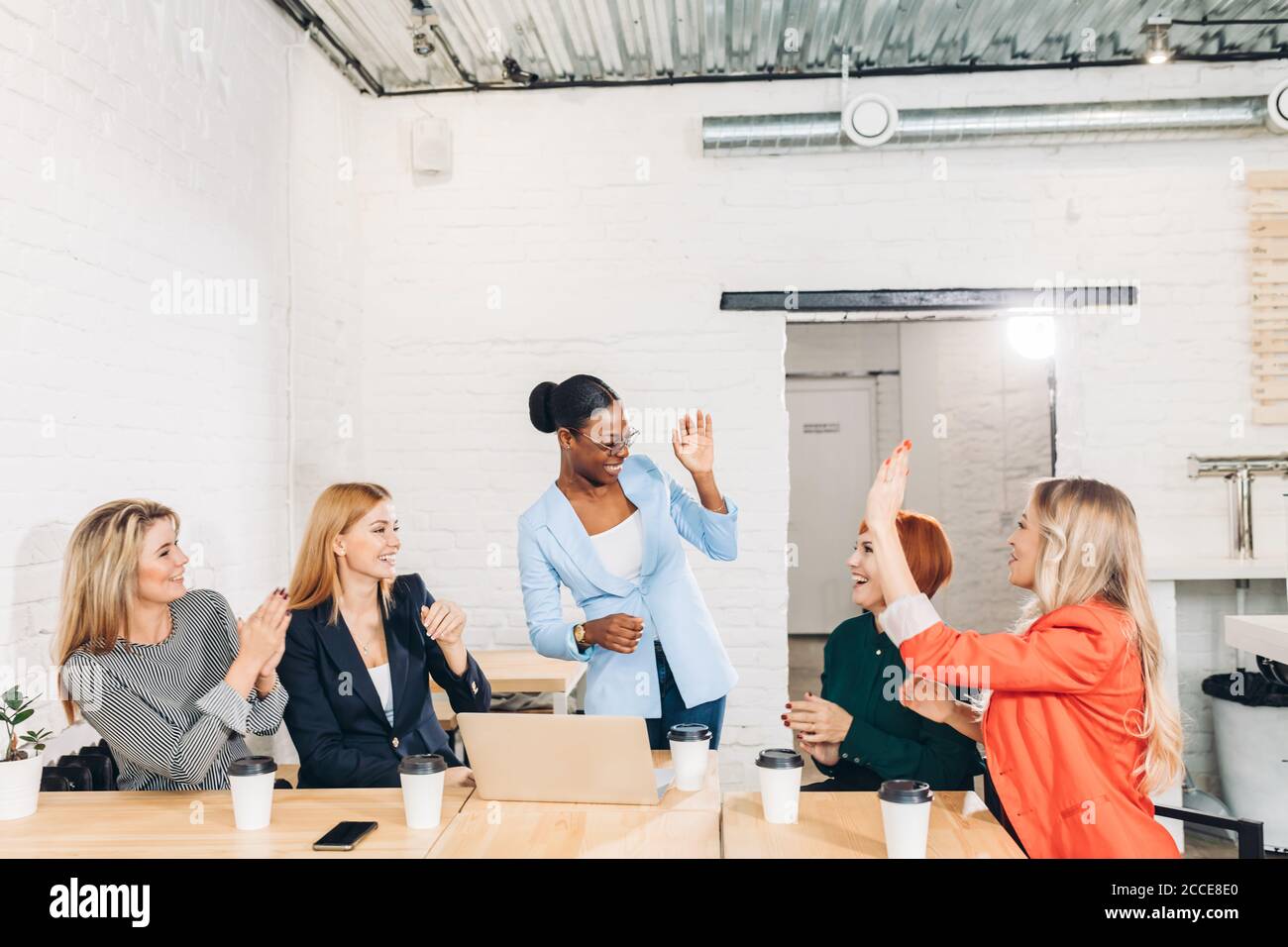 Cheerful young dark-skinned African female Chief giving high five with ...