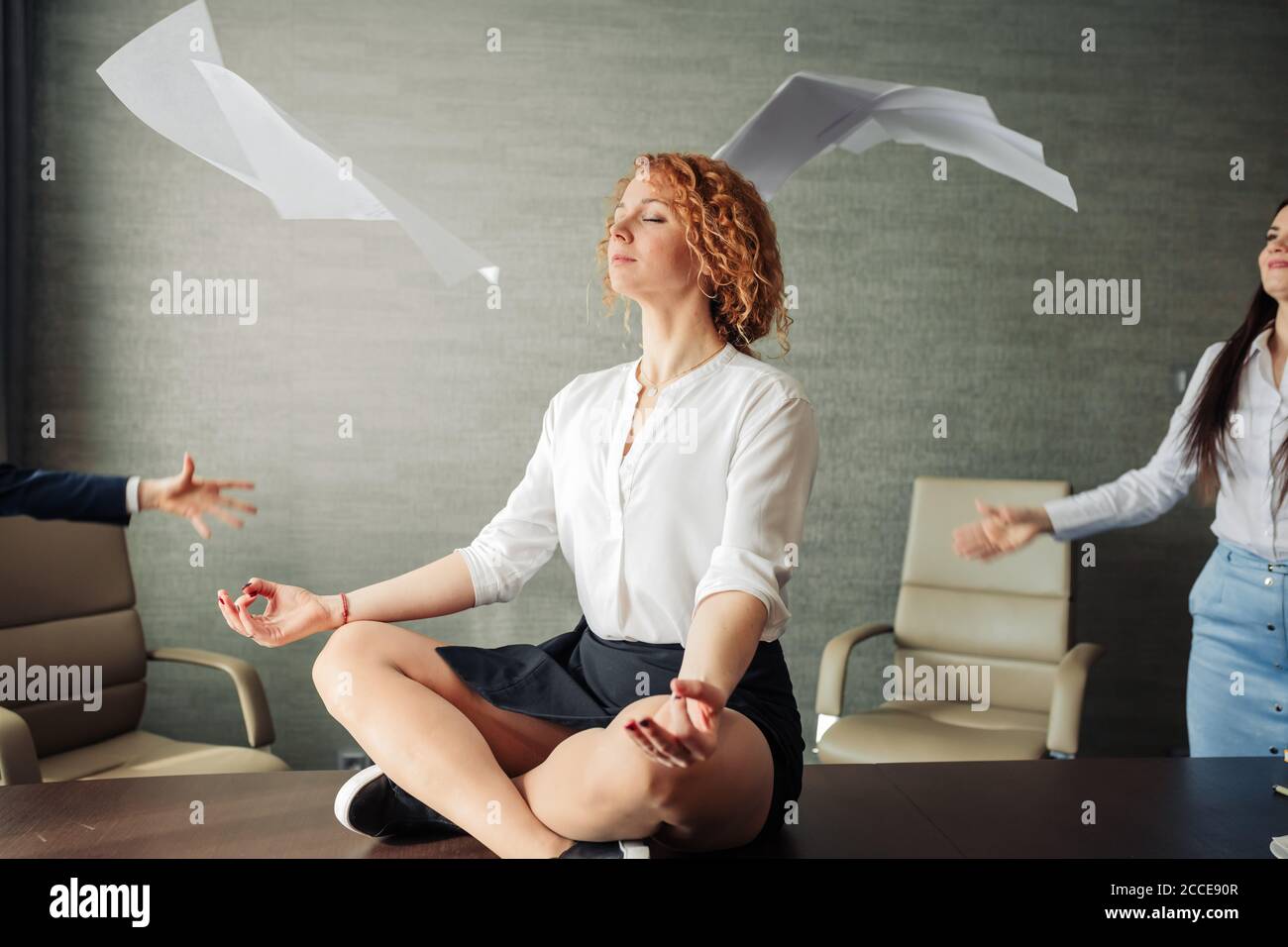 Calm young red-haired woman in formal wear having yoga meditation on ...