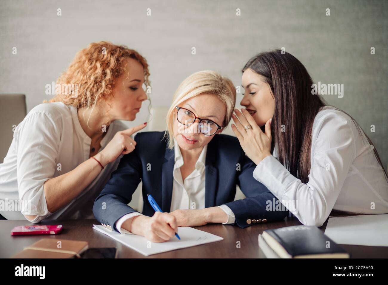 Blonde Business Woman Working Writing A Document And Two Female
