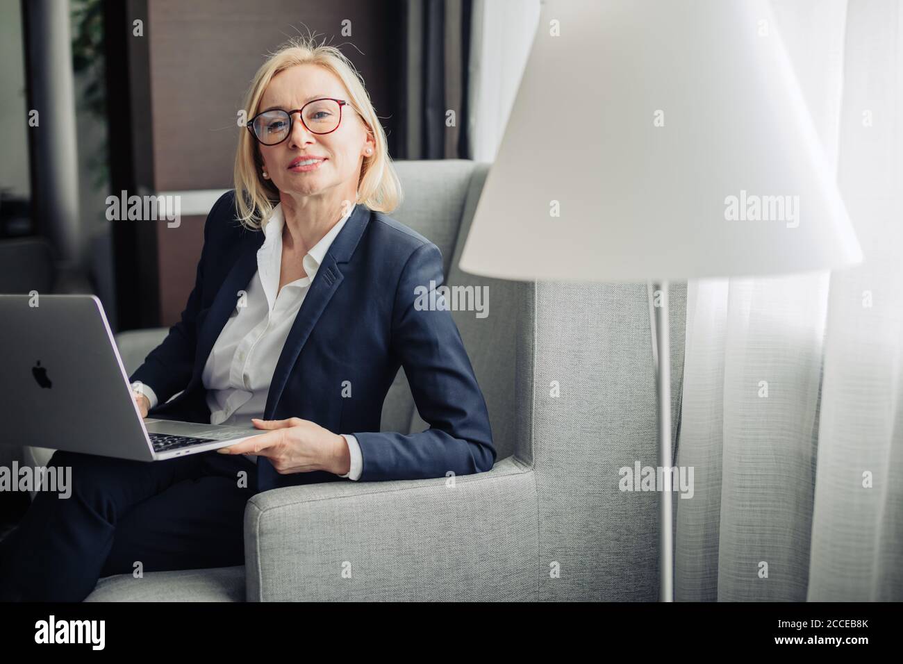 Indoor portrait of glad smiling blond business woman dressed in white ...
