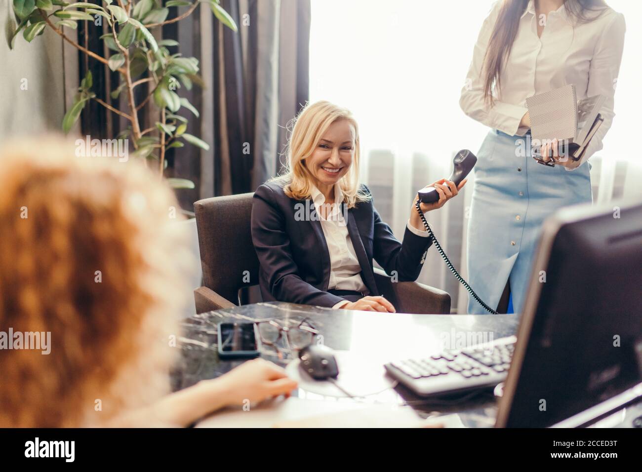 Blonde chief executive businesswoman doing multitasking work in office ...