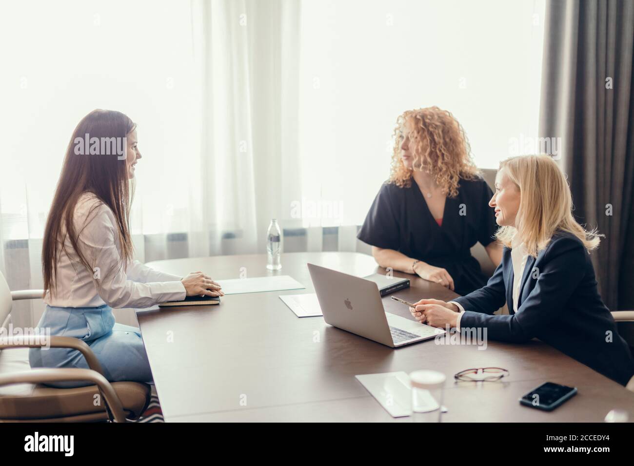 Two young friendly looking female recruiters listening to brunette ...
