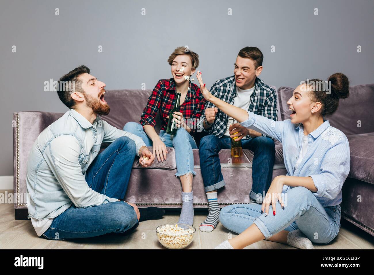 friends are throwing popcorn into the man's mouth. full length photo ...