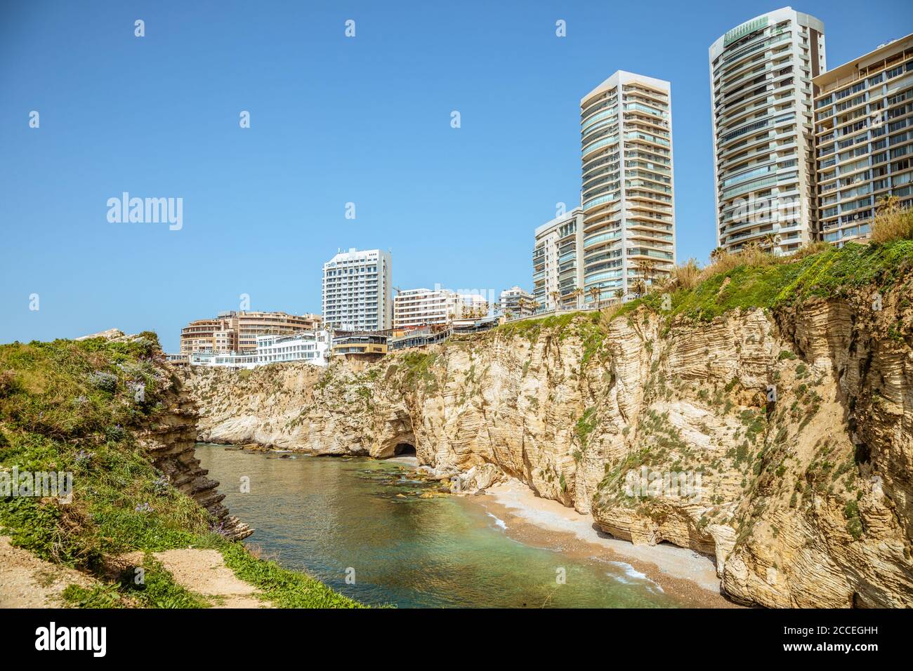 Downtown buildings and towers with rocks and sea in the foreground ...