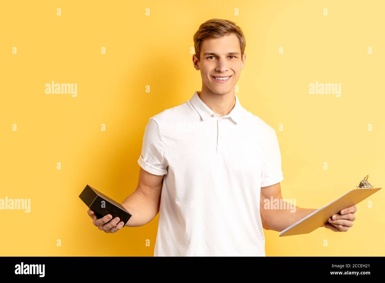 portrait of young caucasian delivery man in unifrom carrying things for ...