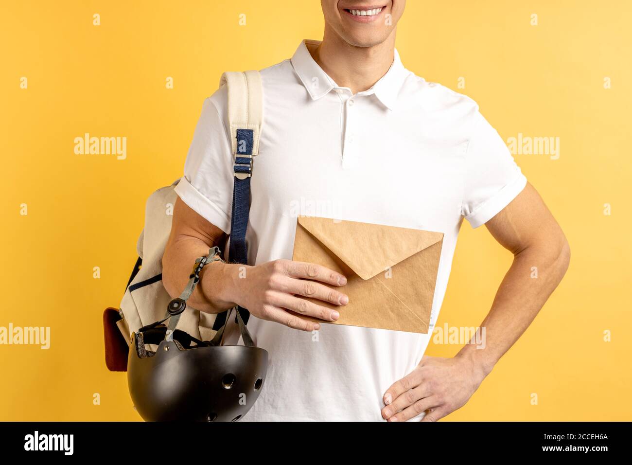 cropped young postman holding letter in hands, wearing white t-shirt ...