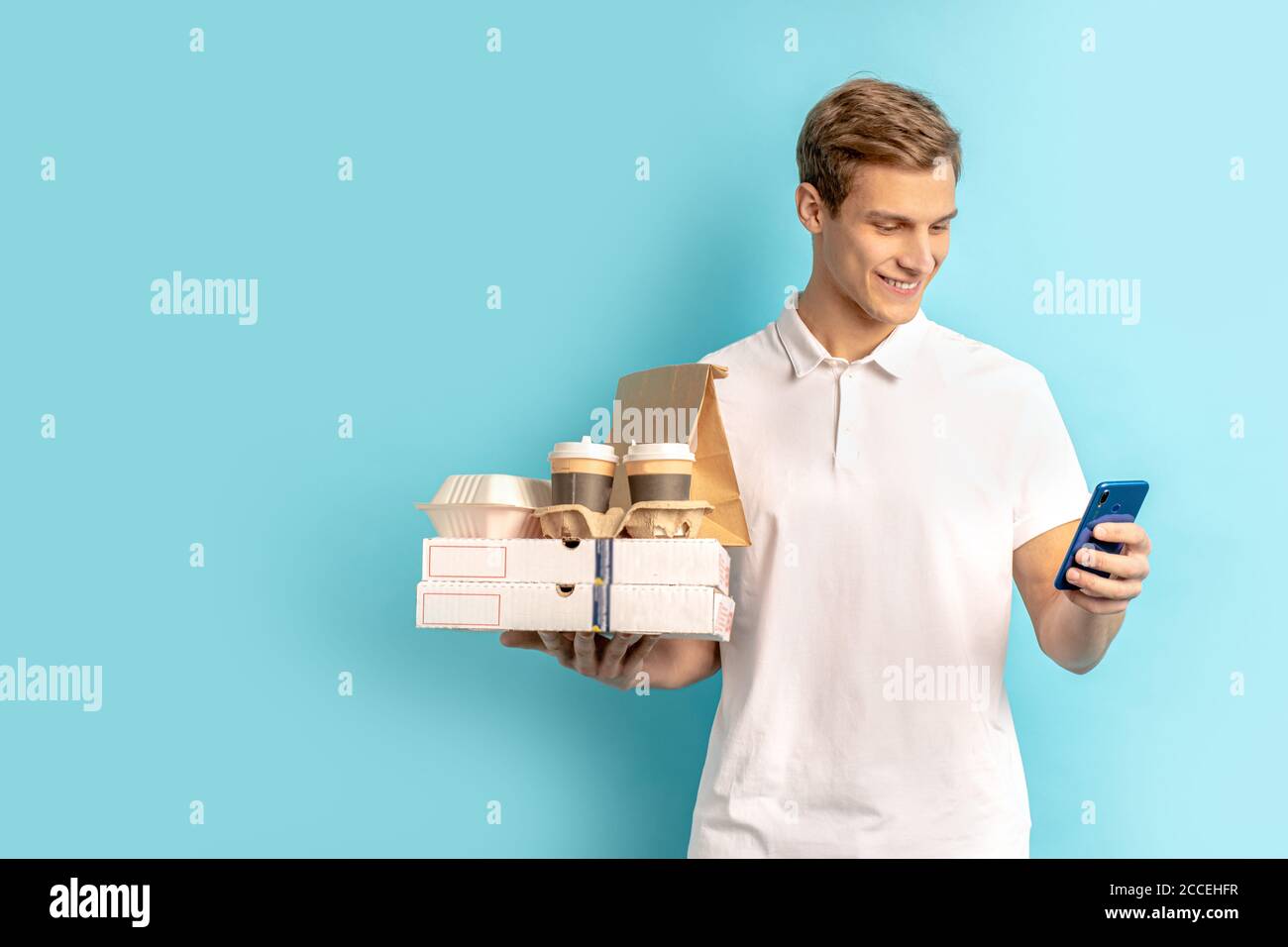 portrait of positive smiling delivery man with smartphone in hands ...