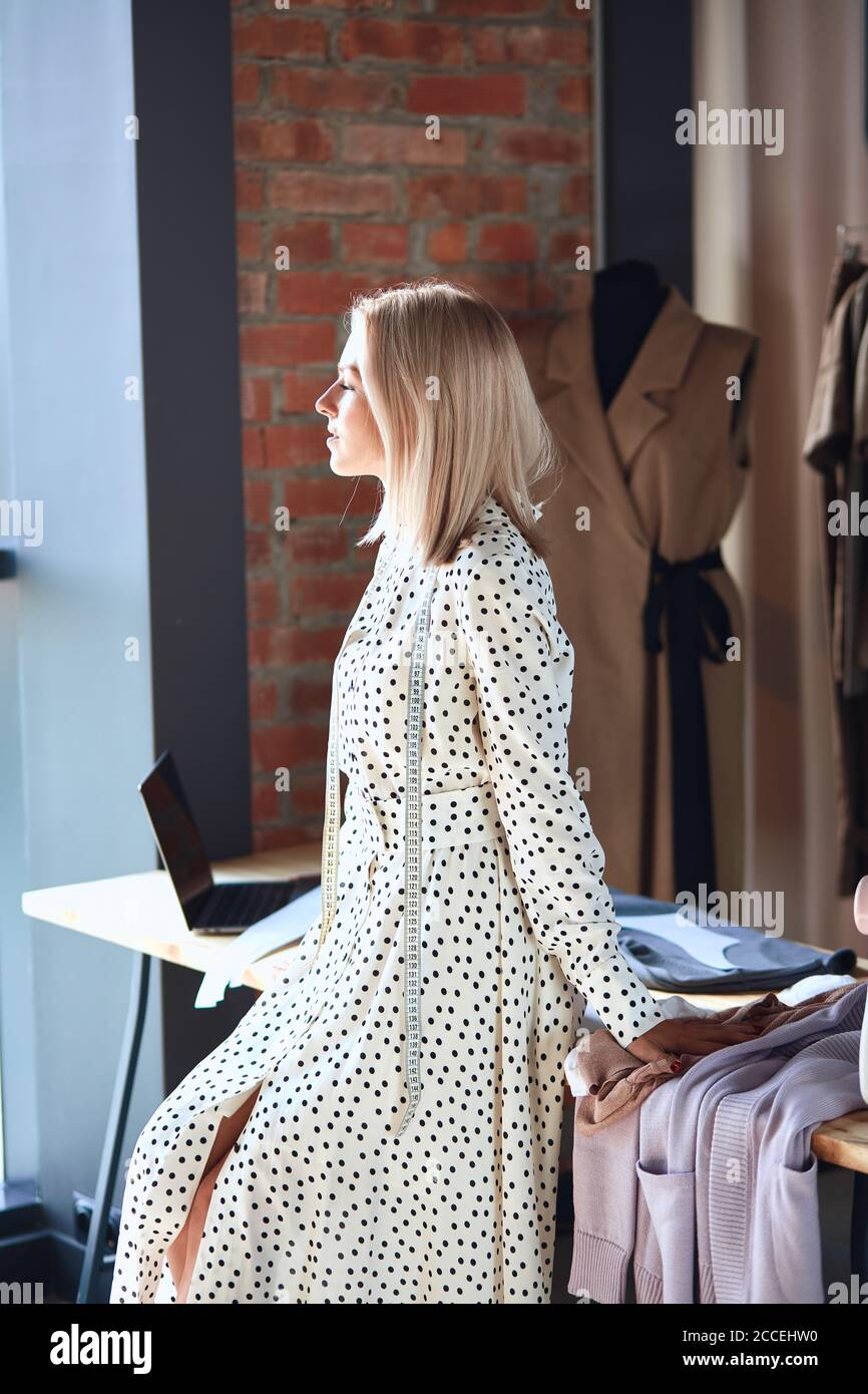 Side view of attractive fashion designer stand at workplace. Dressed in ...