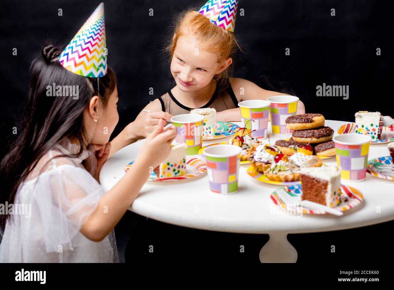 two awesome girl talking while eating birthday cake. closeup photo ...