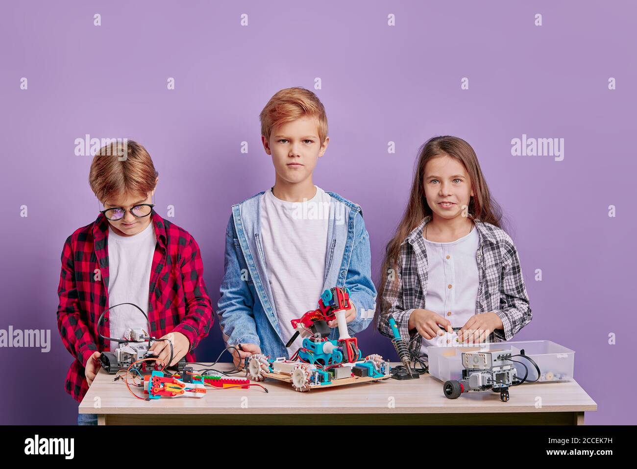portrait of clever children assembling robots on table, teamwork ...